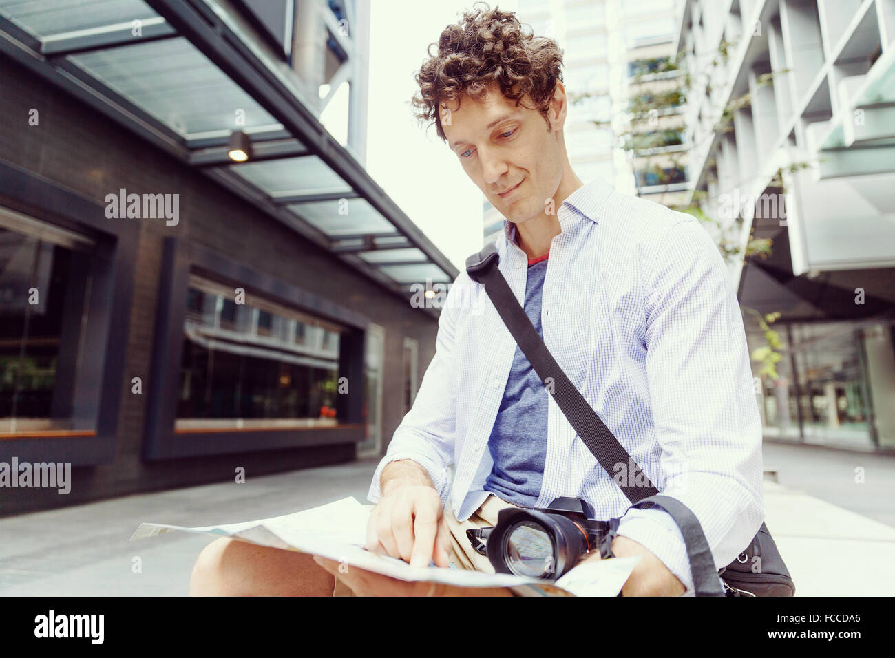 Happy male tourist in city with camera and map Stock Photo - Alamy