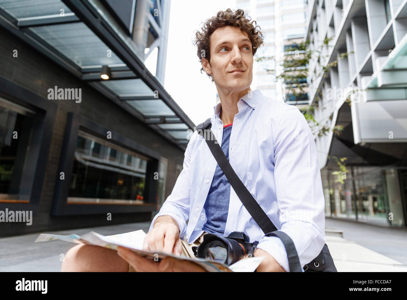 Happy male tourist in city with camera and map Stock Photo - Alamy