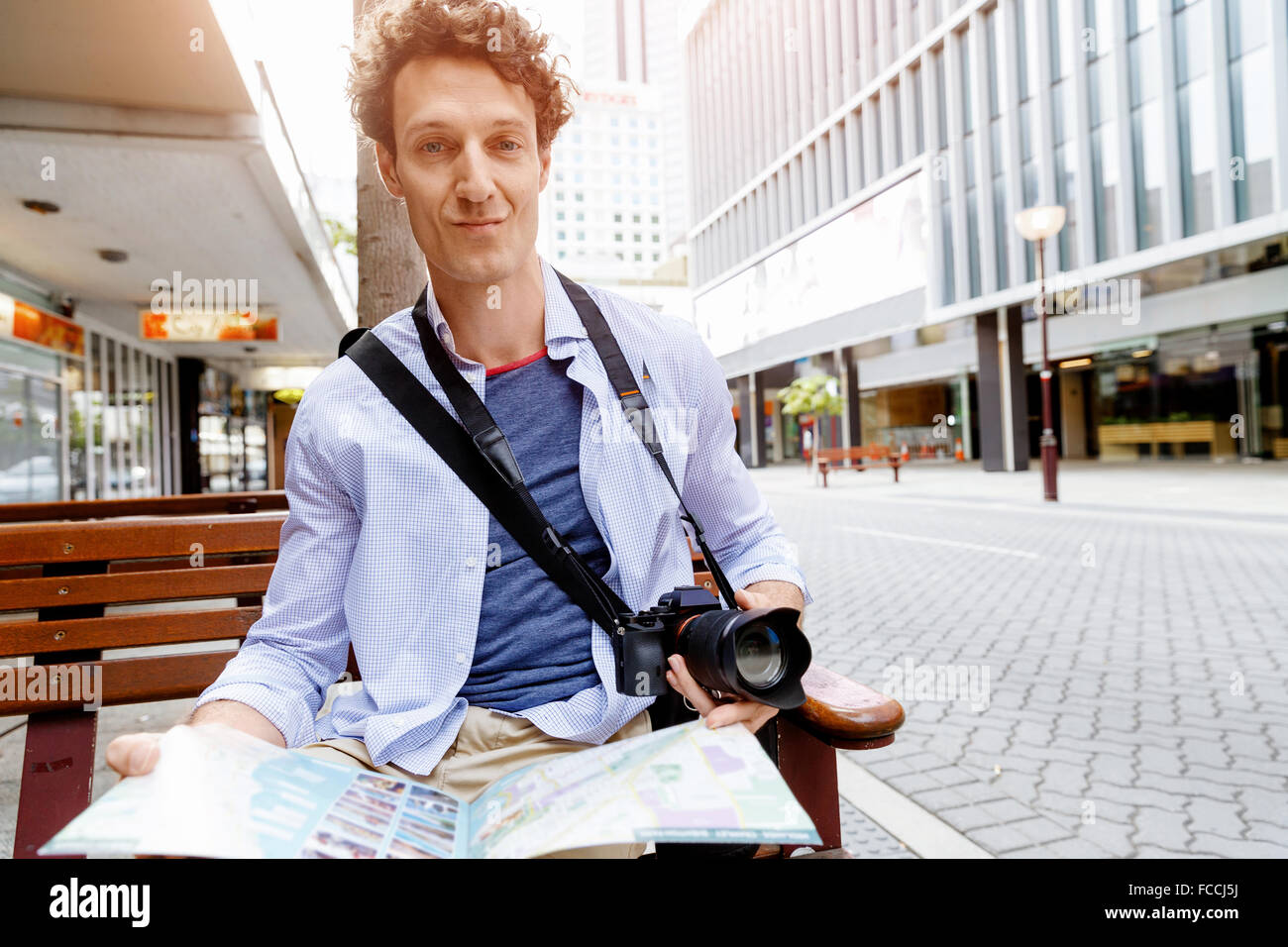 Happy male tourist in city with camera and map Stock Photo - Alamy
