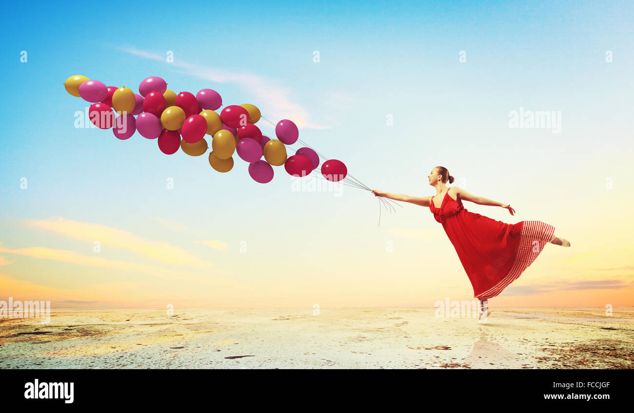 Young woman in dress and ballerinas dancing with colorful balloons ...
