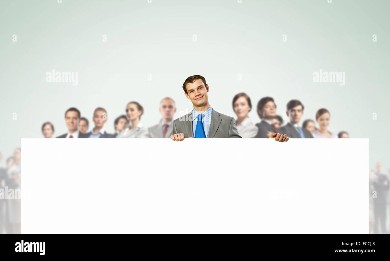 Image of businessman with blank banner standing against crowd of ...