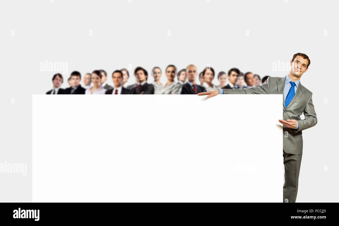 Image of businessman with blank banner standing against crowd of ...