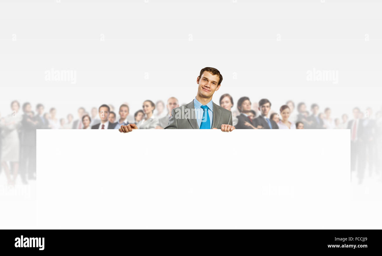 Image of businessman with blank banner standing against crowd of ...