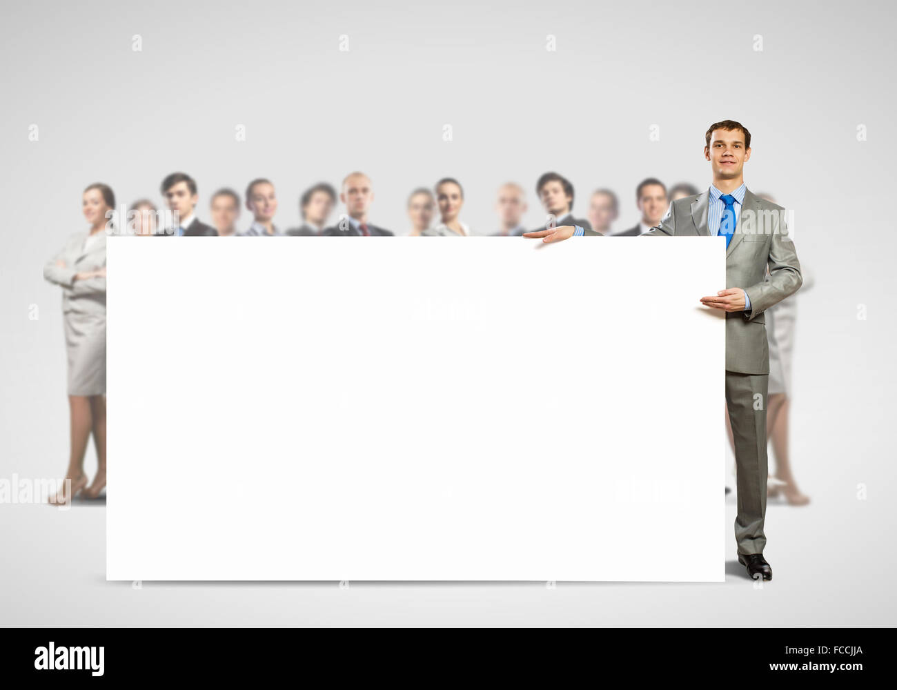 Image of businessman with blank banner standing against crowd of ...