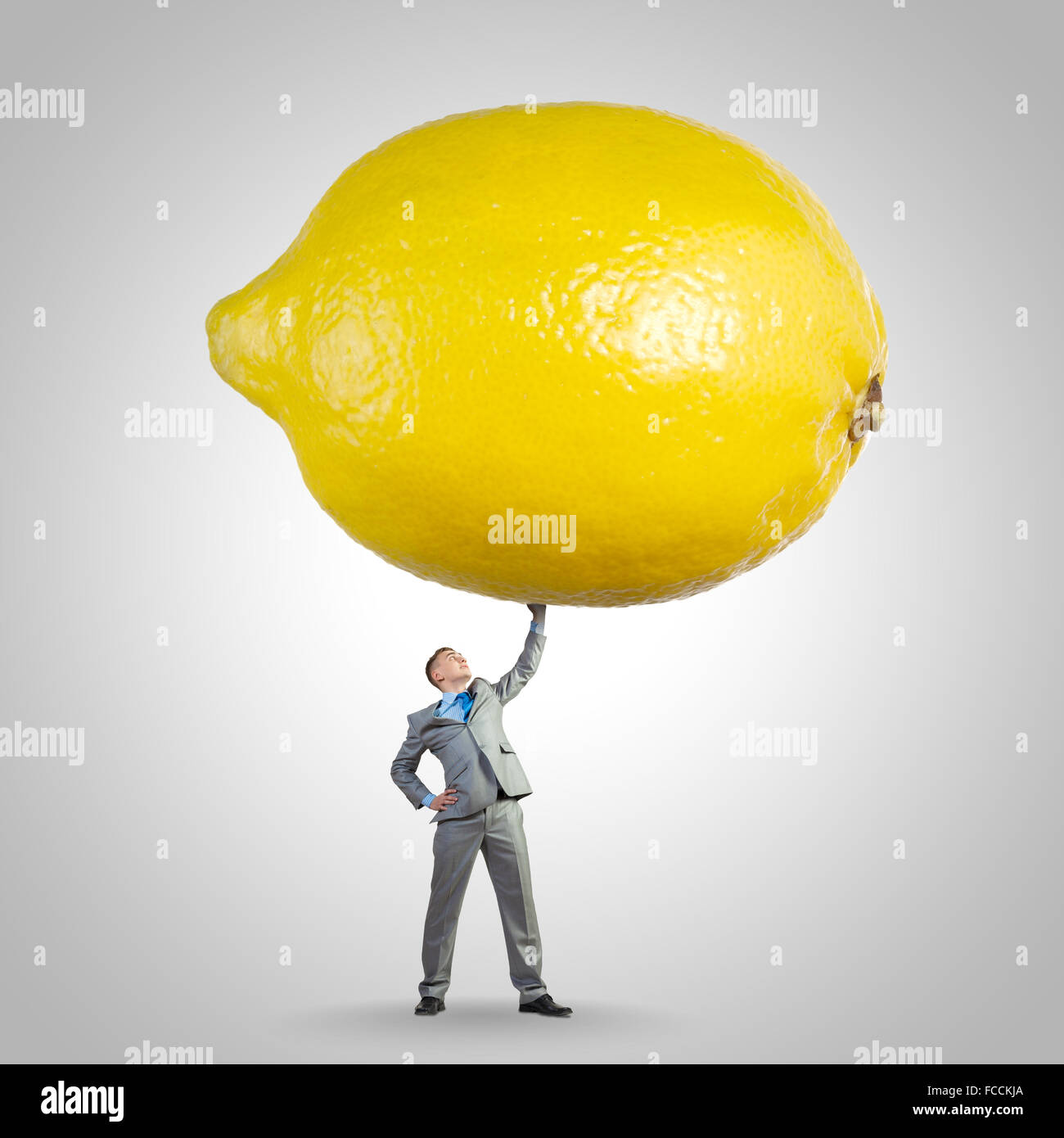Young healthy businessman lifting huge lemon above head Stock Photo - Alamy
