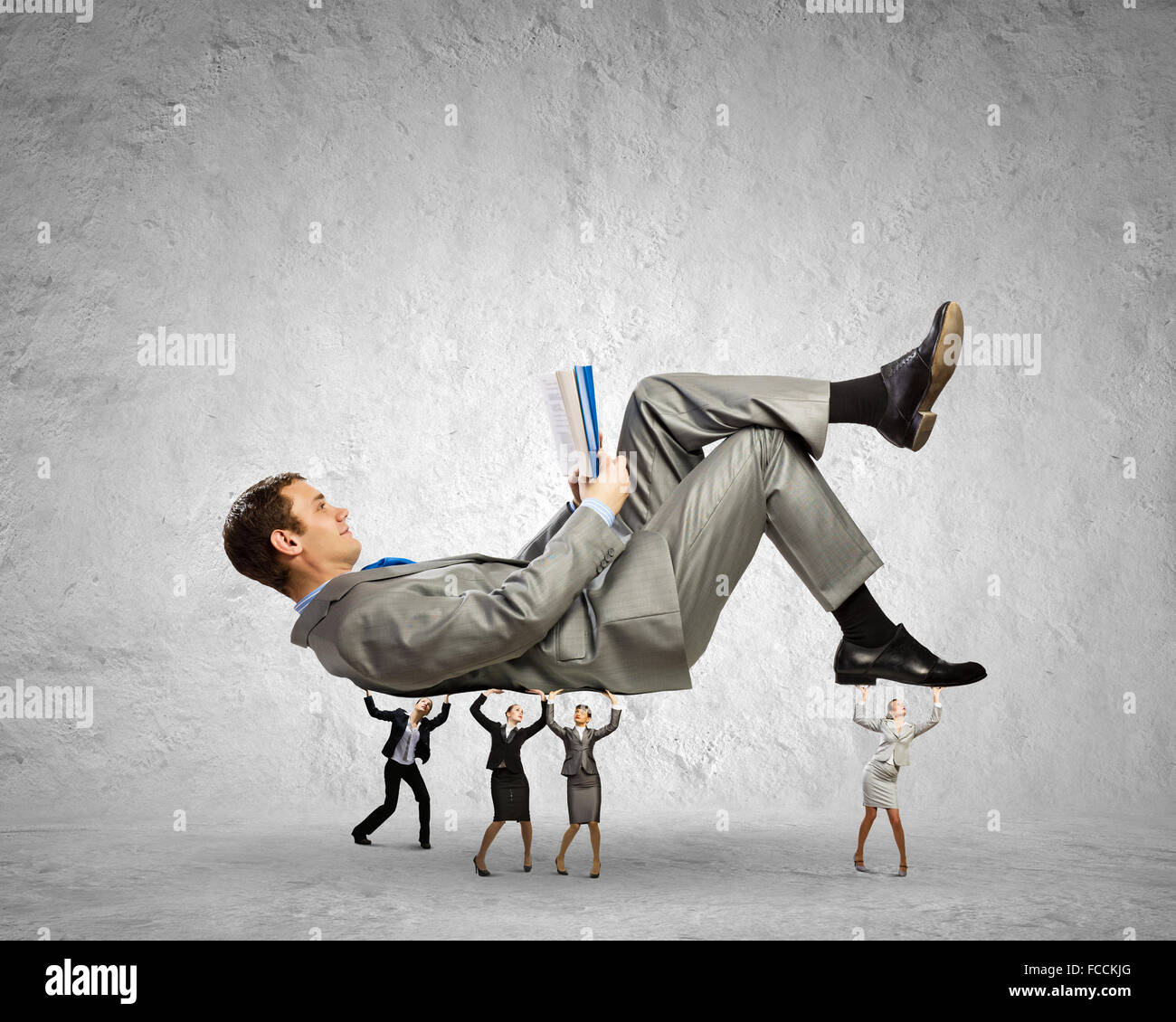 Young businessman lying and reading book supported by colleagues Stock ...