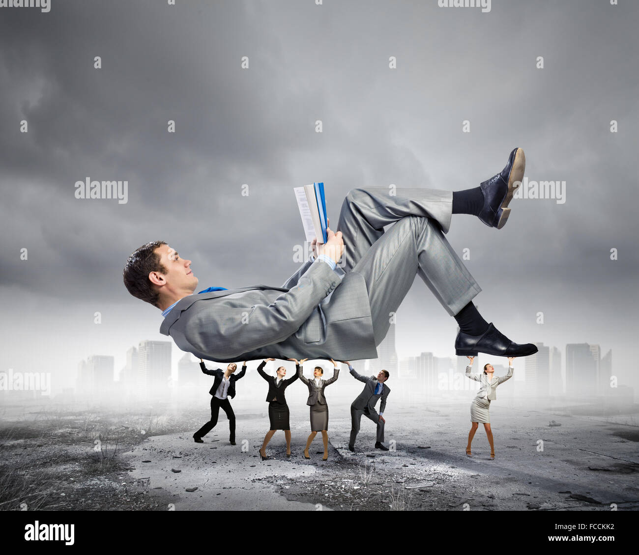 Young businessman lying and reading book supported by colleagues Stock ...