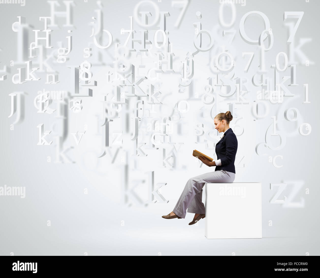 Young attractive woman sitting on white cube and reading book Stock ...