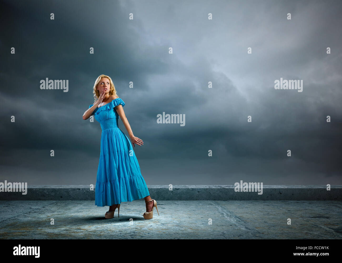 Anxious young woman in blue dress looking back worried Stock Photo - Alamy