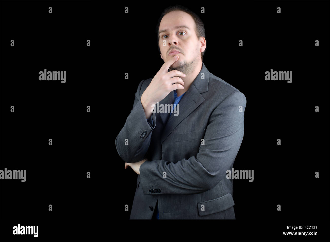 young man dark gray suite thinking holding chin Stock Photo - Alamy