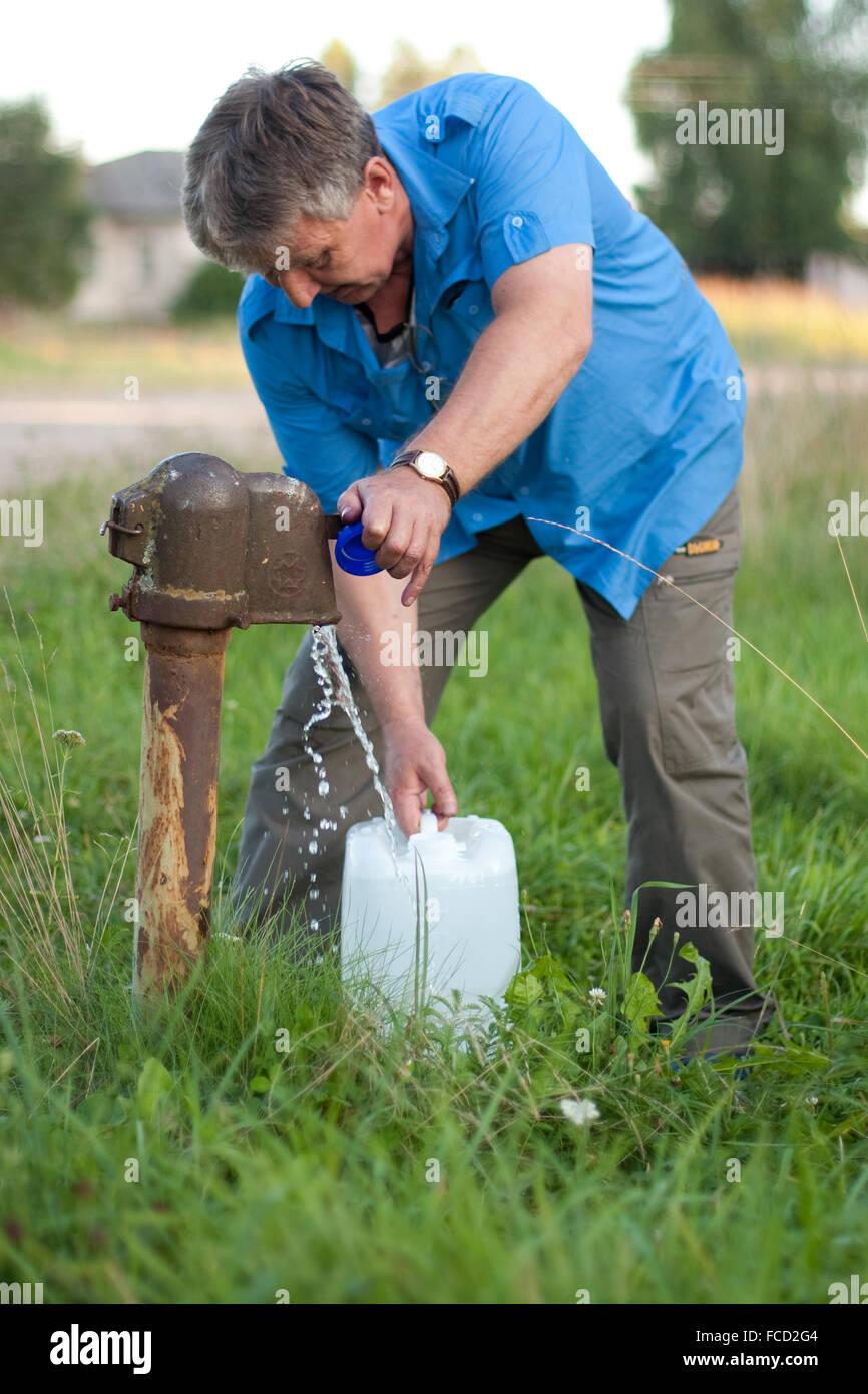 A man collects the water from the old water pump Stock Photo - Alamy