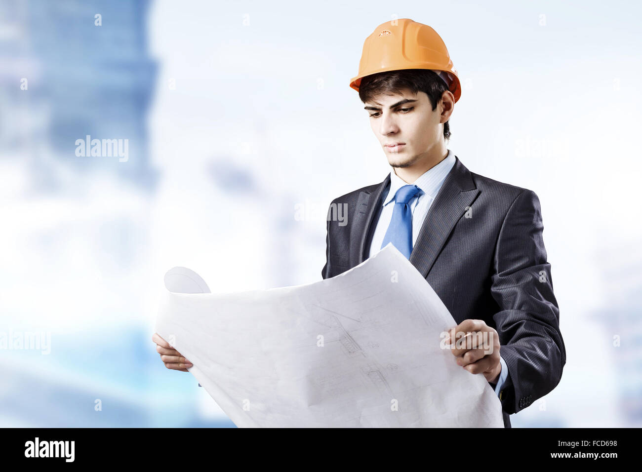 Young man engineer in helmet examining construction project Stock Photo ...