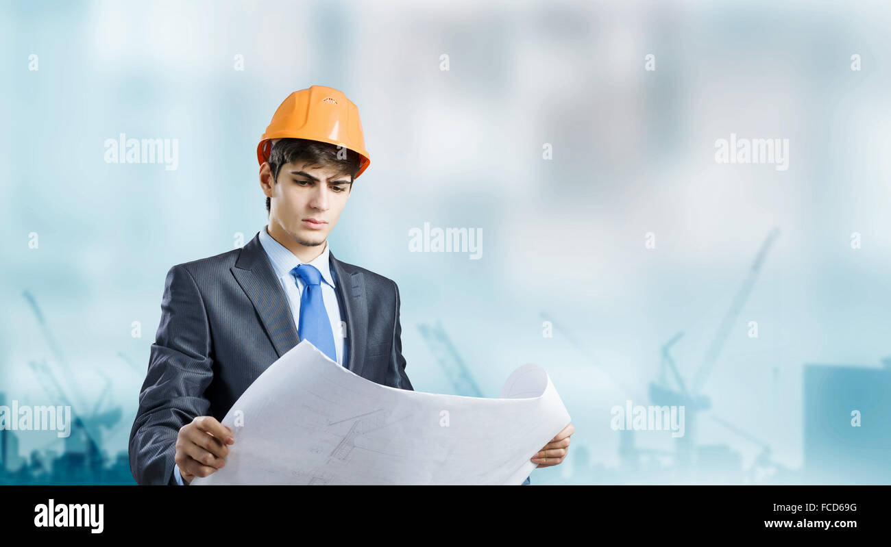 Young man engineer in helmet examining construction project hi-res ...