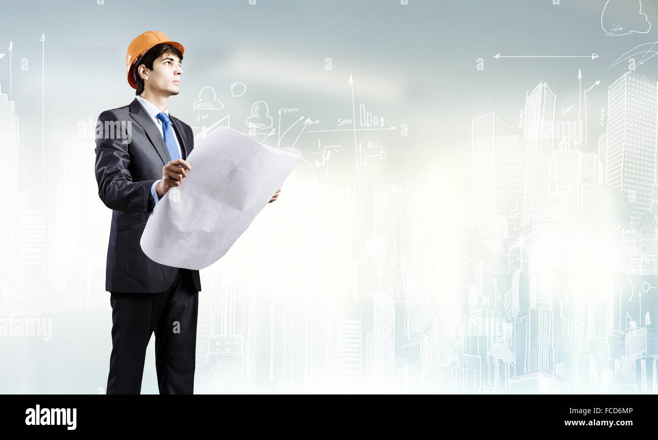 Young man engineer in helmet examining construction project Stock Photo - Alamy