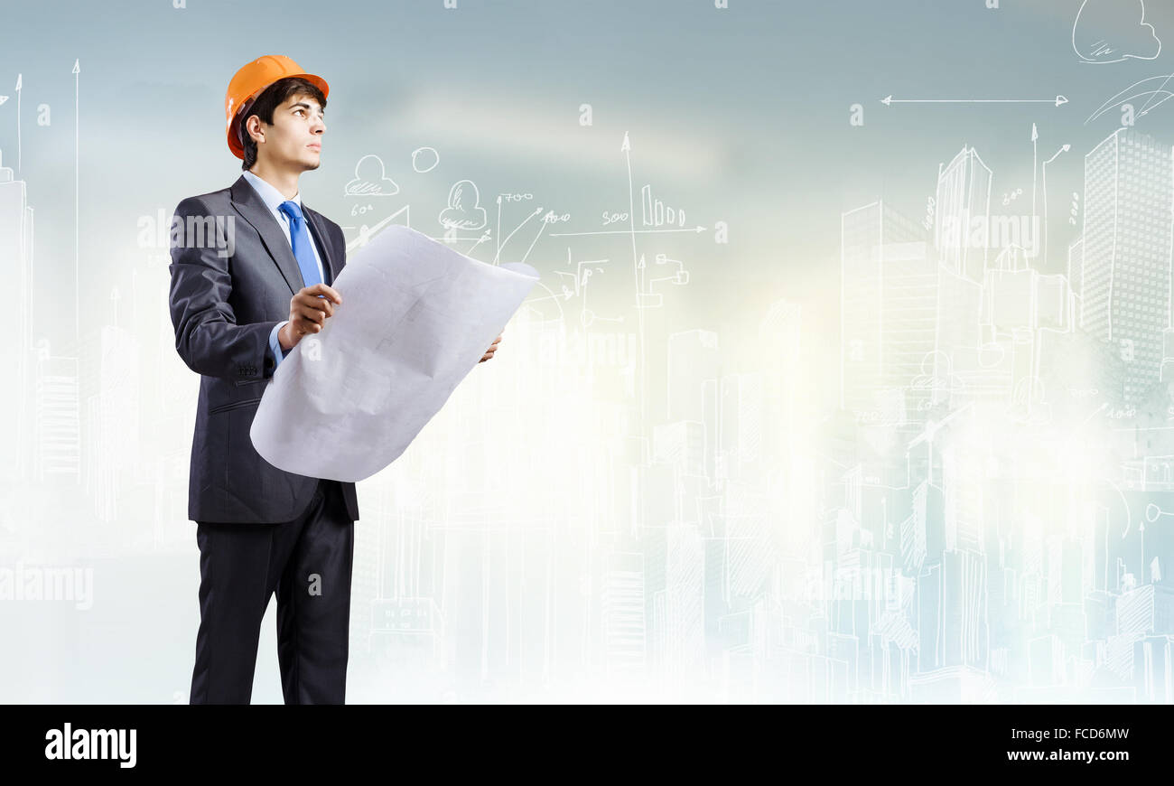 Young man engineer in helmet examining construction project Stock Photo ...