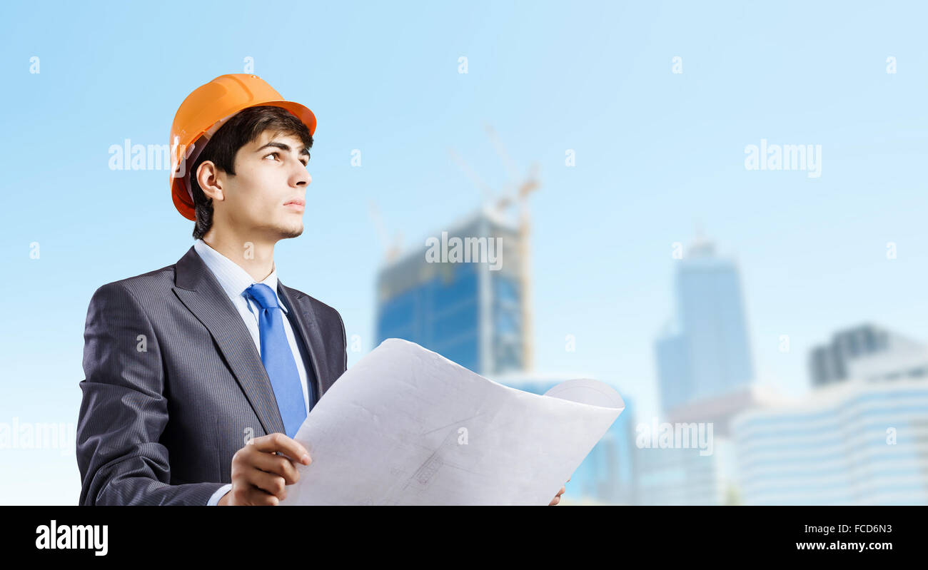 Young man engineer in helmet examining construction project Stock Photo ...
