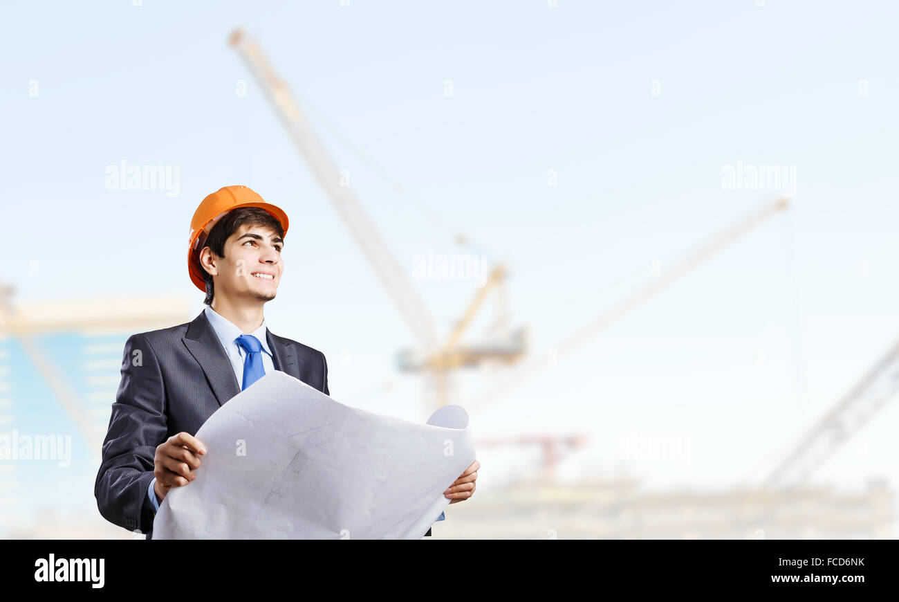 Young man engineer in helmet examining construction project Stock Photo ...