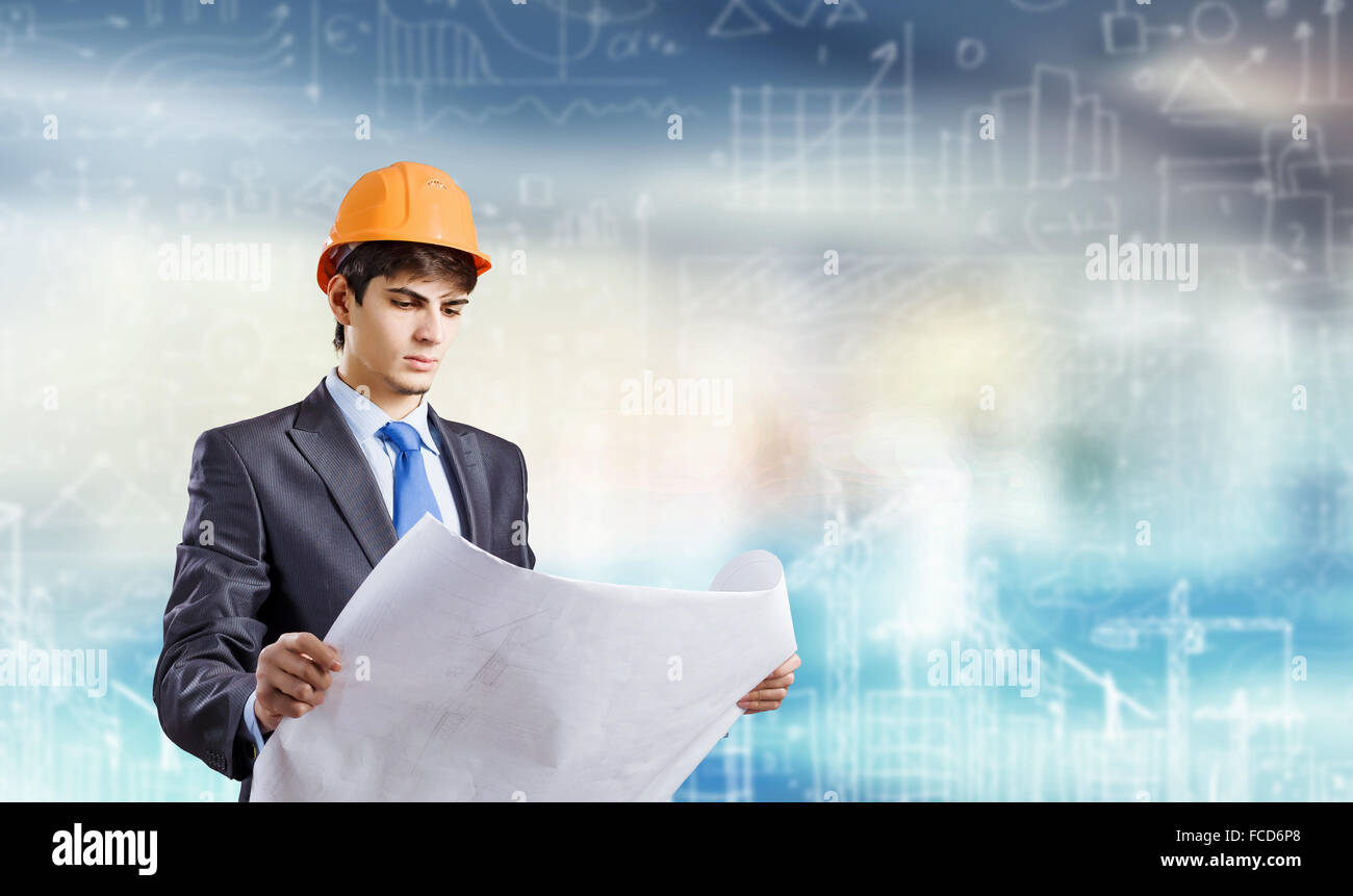 Young man engineer in helmet examining construction project Stock Photo - Alamy