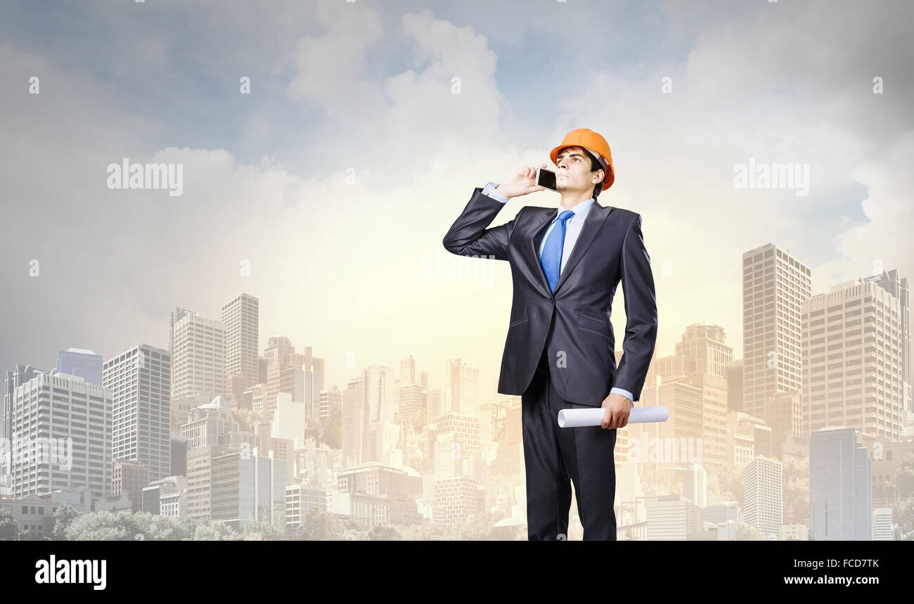 Young man engineer in helmet talking on mobile phone Stock Photo - Alamy