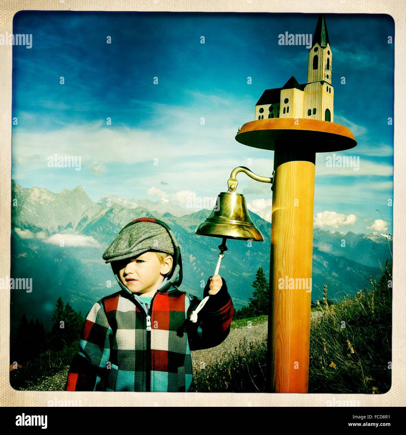 Cute Boy Ringing Bell Against Mountains Stock Photo - Alamy
