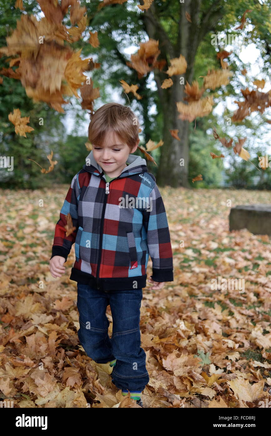 Autumn Leaves Falling On Boy In Park Stock Photo - Alamy