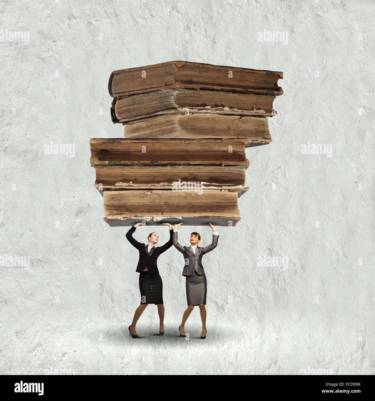 Two young ladies lifting pile of old books above head Stock Photo - Alamy