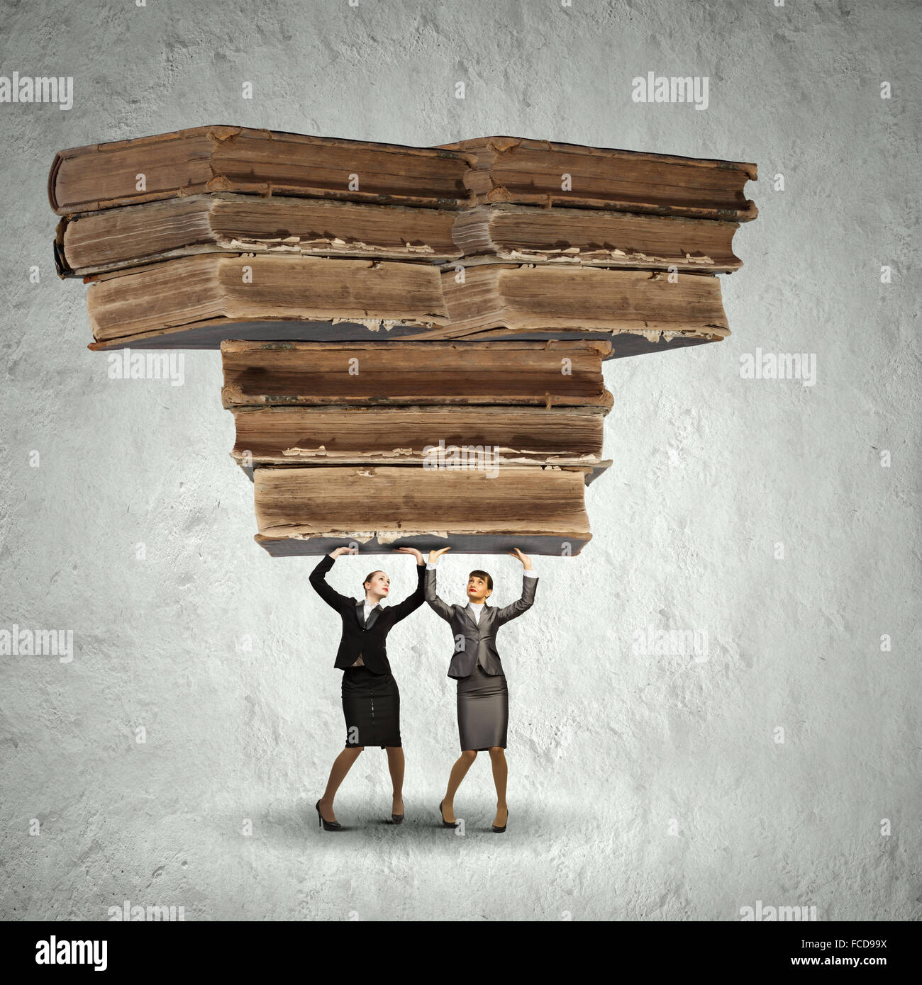 Two young ladies lifting pile of old books above head Stock Photo - Alamy