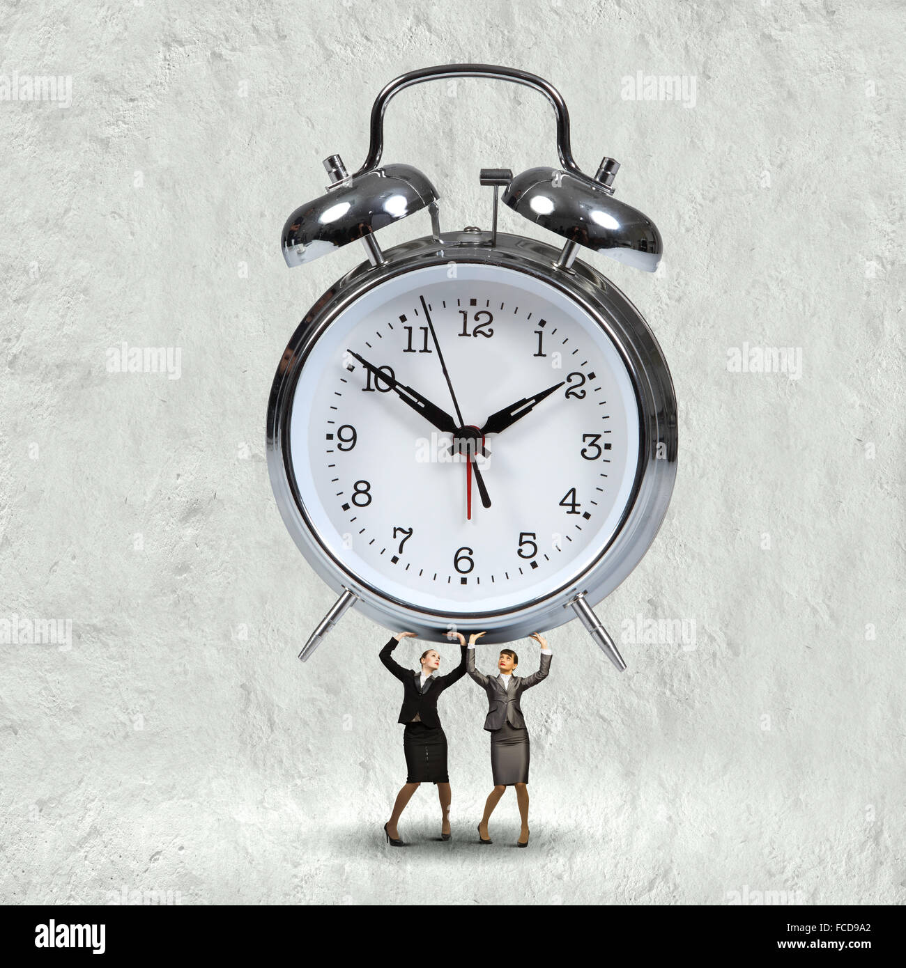 Two businesswoman lifting huge alarm clock above head Stock Photo - Alamy