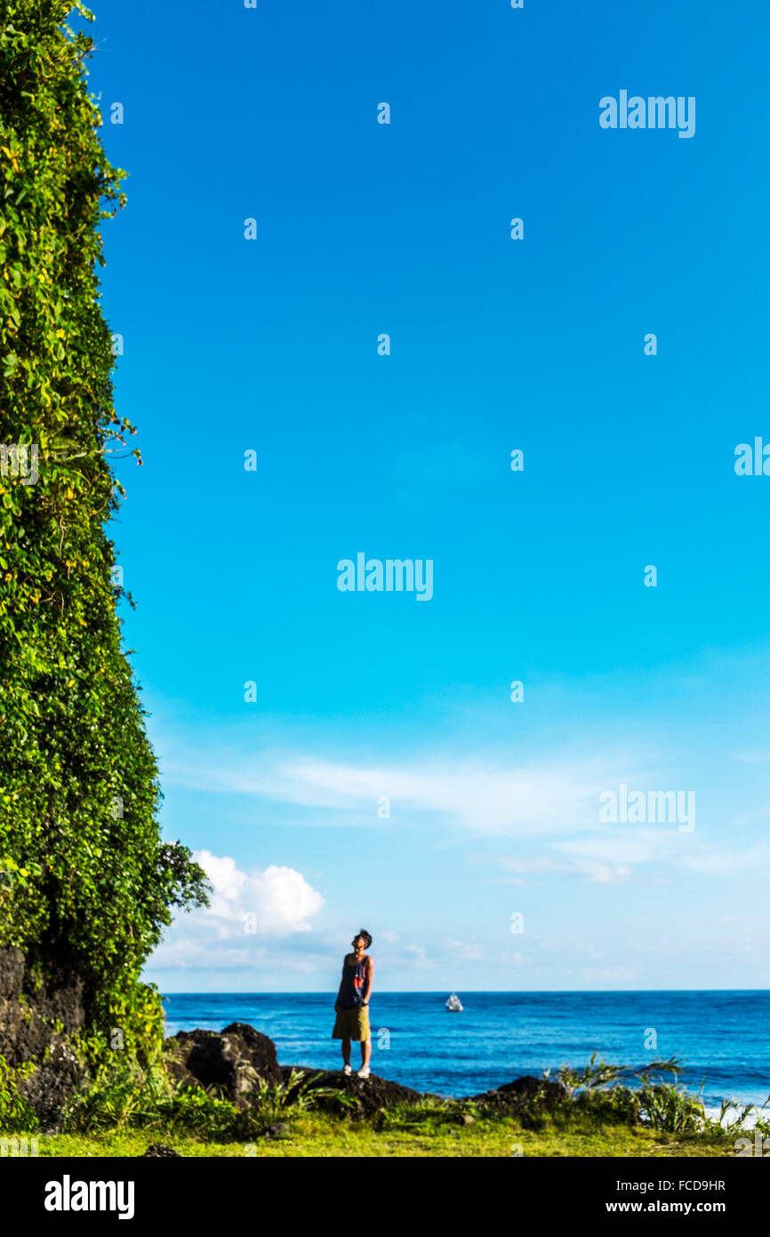 Man Looking Up At Overgrown Rock At Seaside Stock Photo - Alamy