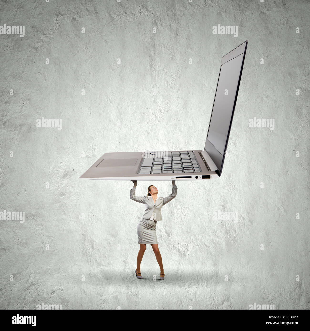 Young businesswoman lifting huge laptop above head Stock Photo - Alamy