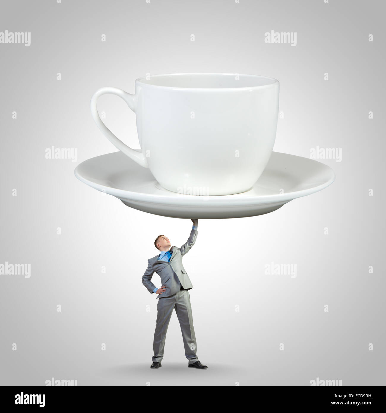 Young businessman lifting huge cup of coffee with one hand Stock Photo ...