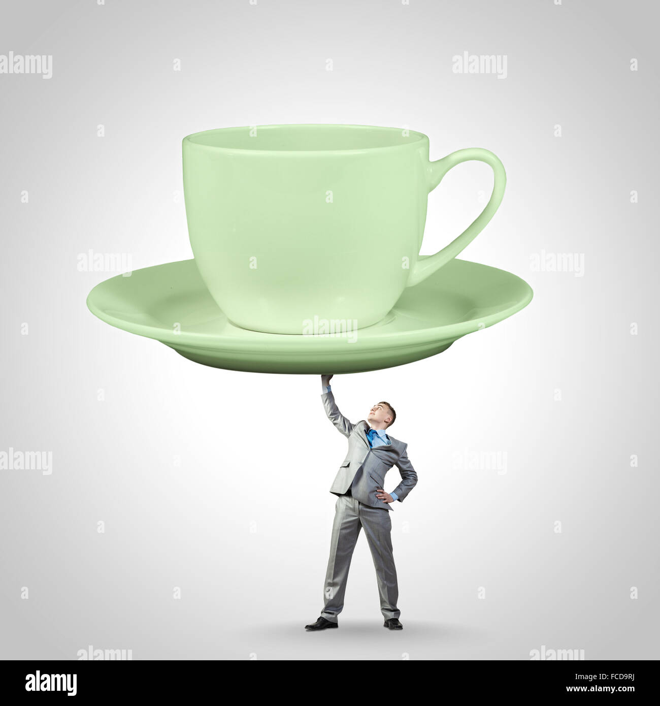 Young businessman lifting huge cup of coffee with one hand Stock Photo ...
