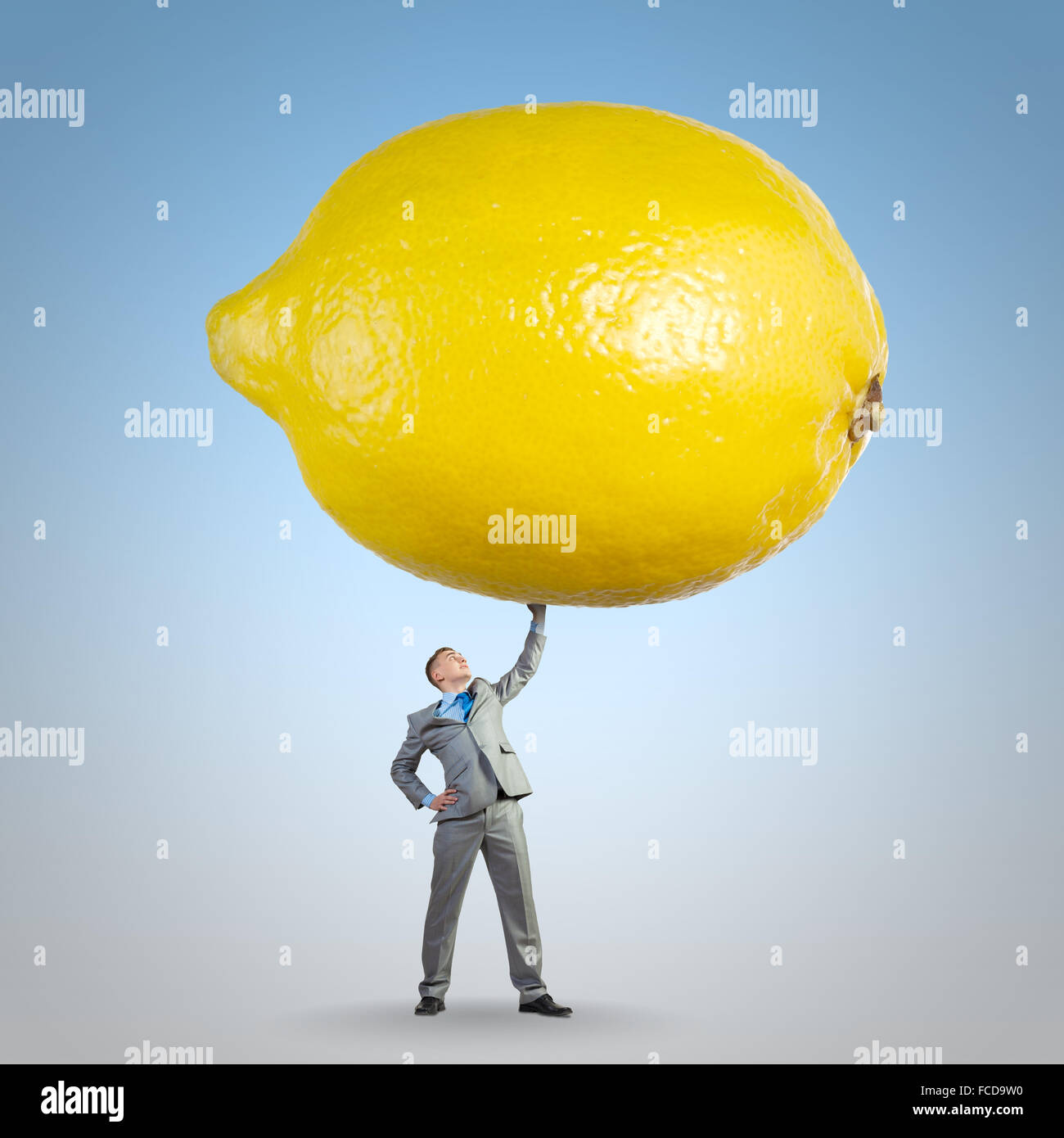 Young healthy businessman lifting huge lemon above head Stock Photo - Alamy