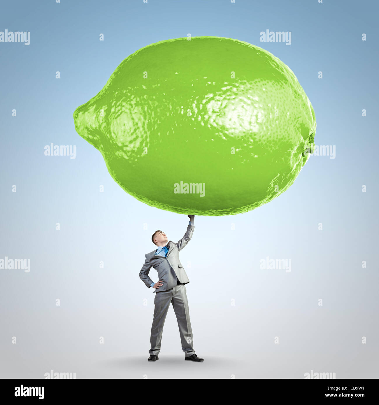 Young healthy businessman lifting huge lime above head Stock Photo - Alamy