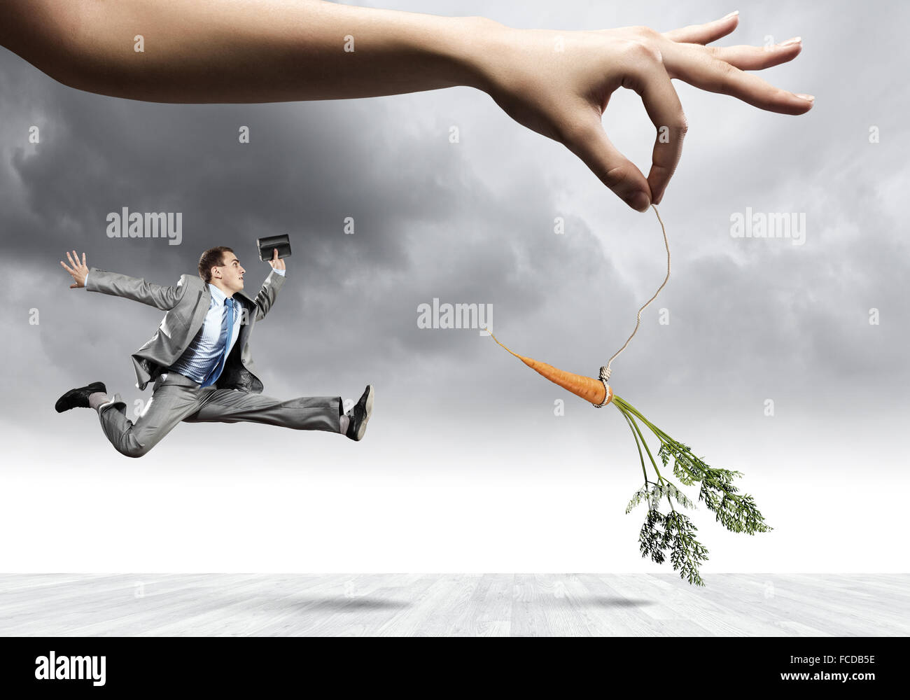 Funny image of businessman chased with carrot Stock Photo - Alamy