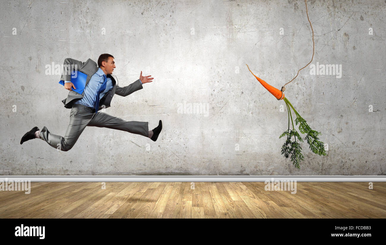 Funny image of businessman chased with carrot Stock Photo - Alamy