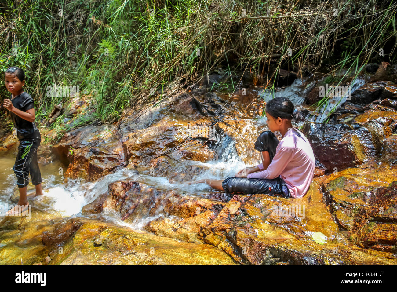 Children playing on wet rocks of a waterfall Stock Photo - Alamy