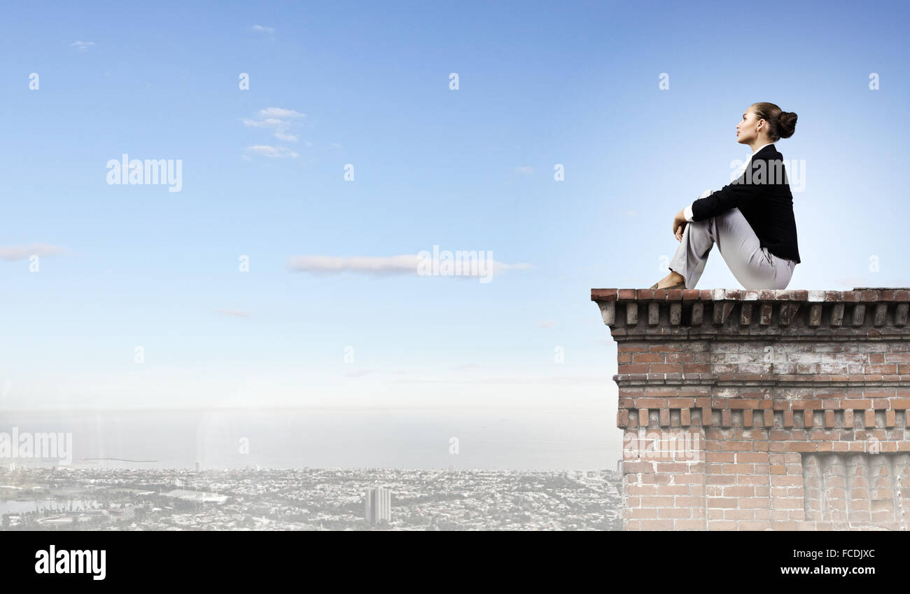 Young attractive lady sitting on top of building Stock Photo - Alamy
