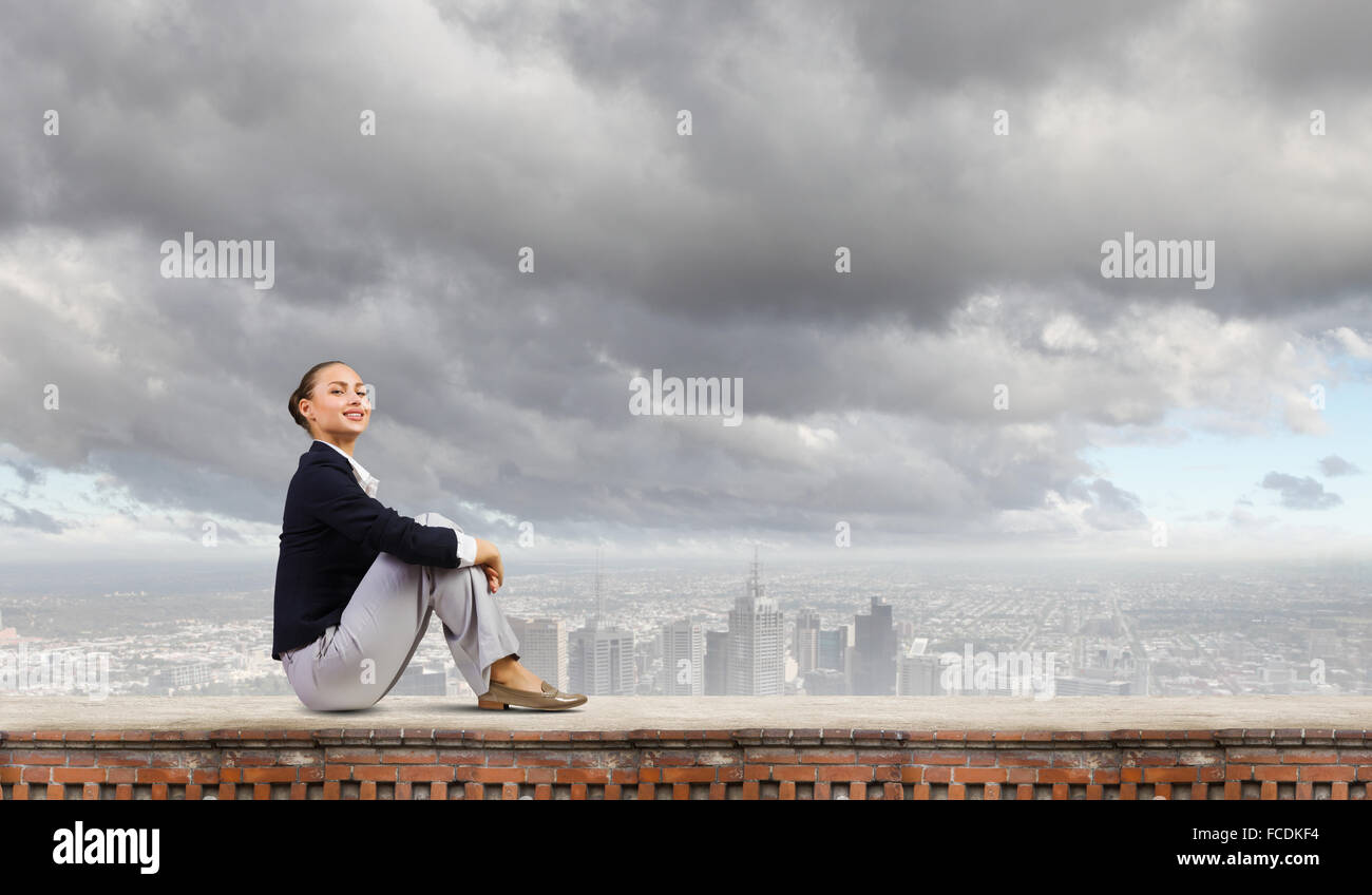 Young attractive lady sitting on top of building Stock Photo - Alamy