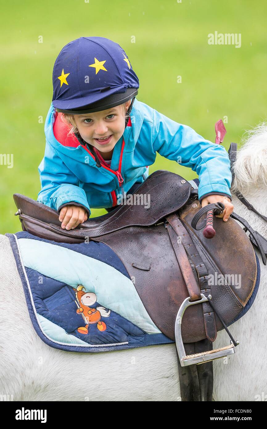 Welsh Mountain Pony, Section A. Girl mounting gray pony. Germany Stock ...