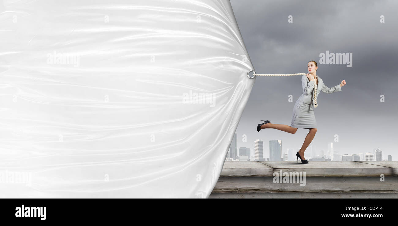 Young businesswoman running and pulling white blank banner Stock Photo ...