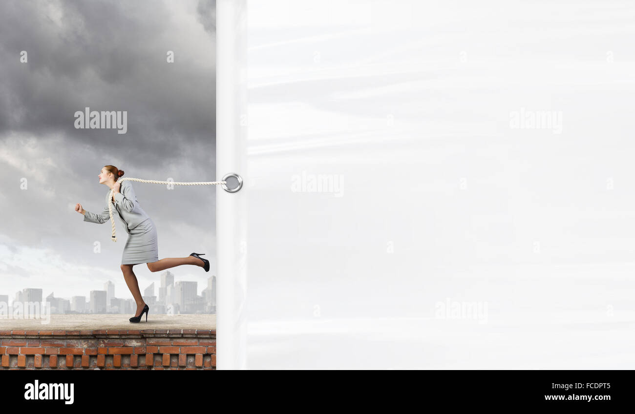 Young businesswoman running and pulling white blank banner Stock Photo ...