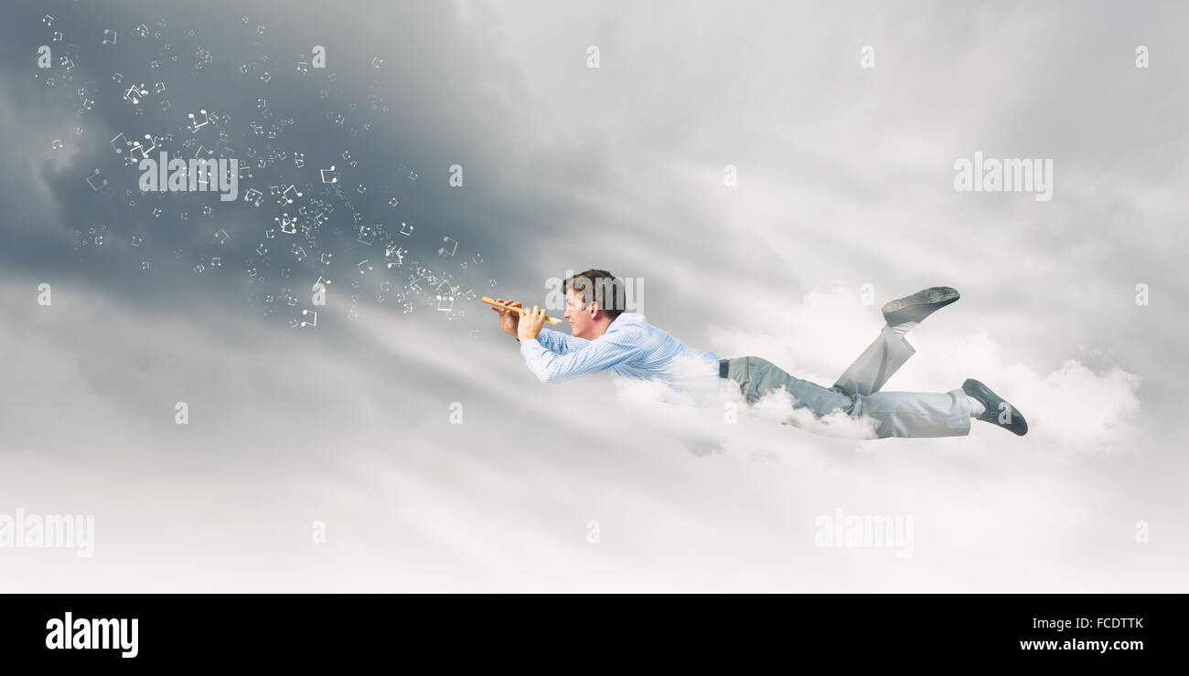 Young businessman flying in sky and playing fife Stock Photo - Alamy