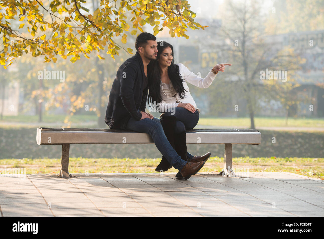 Young Couple Searching Goal In The Distance While Sitting On A Bench ...