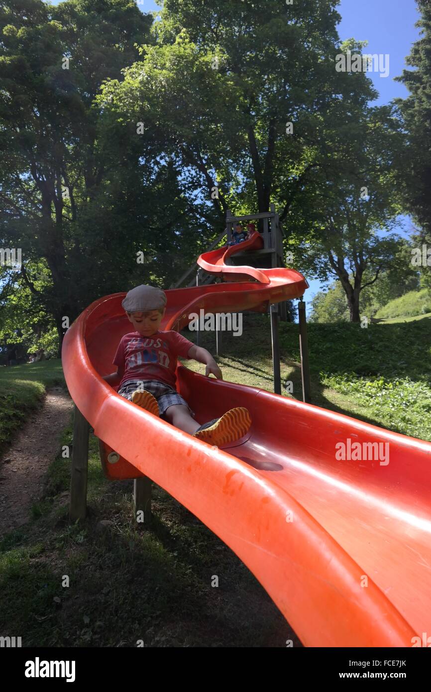 Cute Little Boy On Slide Against Trees Stock Photo - Alamy