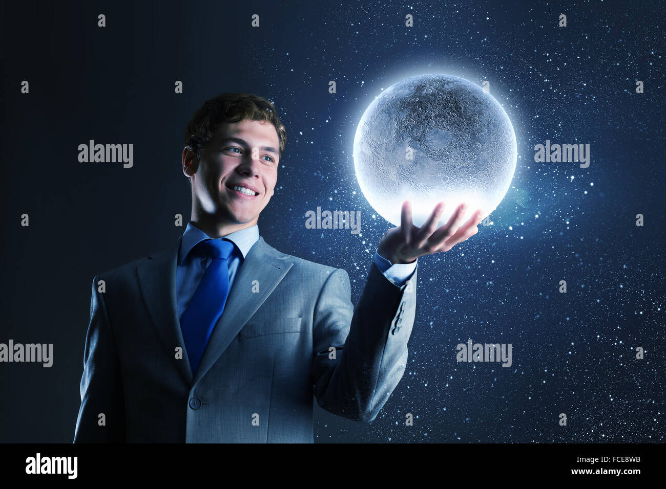 Young man in suit holding moon in palm Stock Photo - Alamy