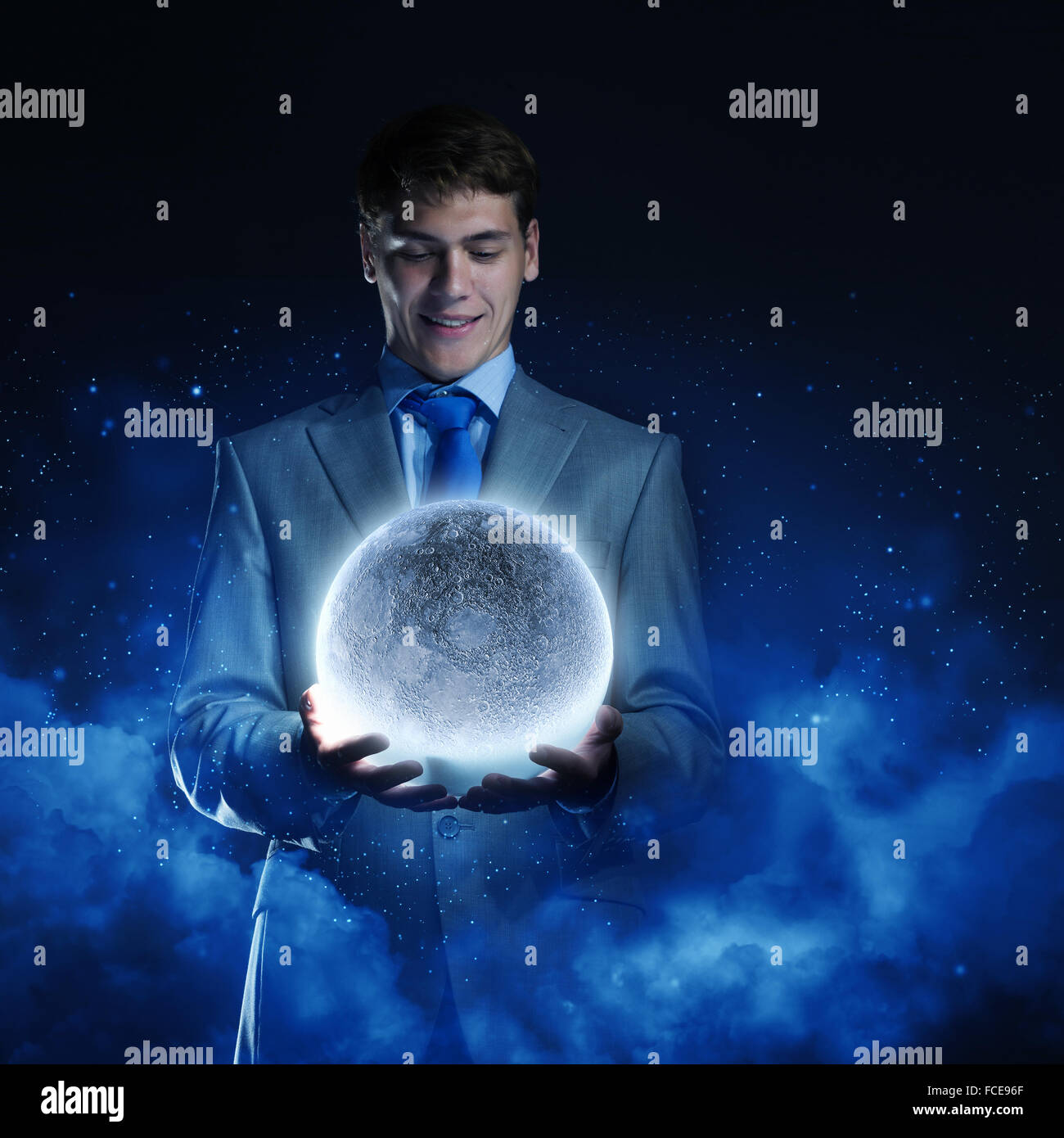 Young man in suit holding moon in palm Stock Photo - Alamy
