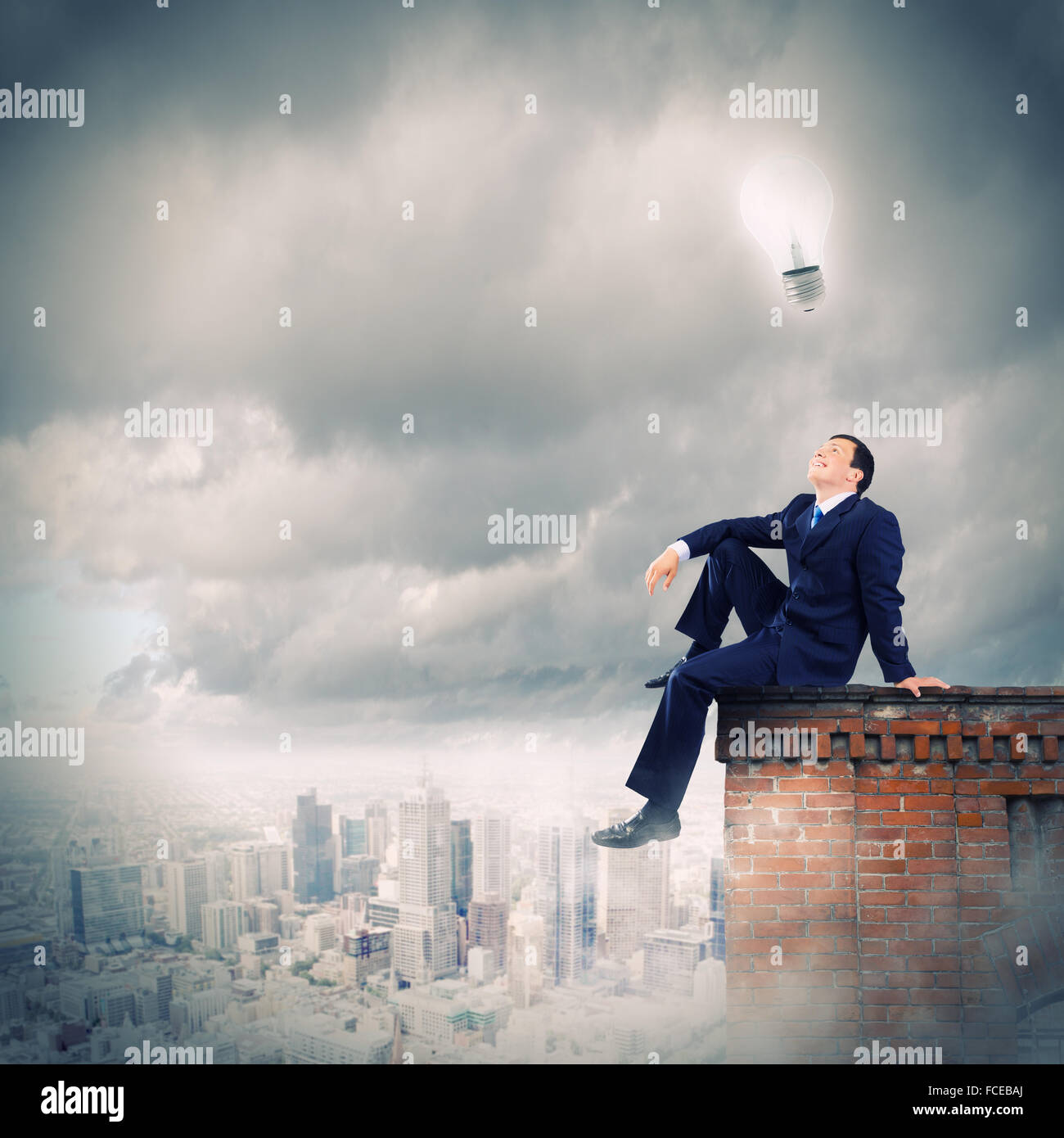 Young businessman sitting on roof of building Stock Photo - Alamy