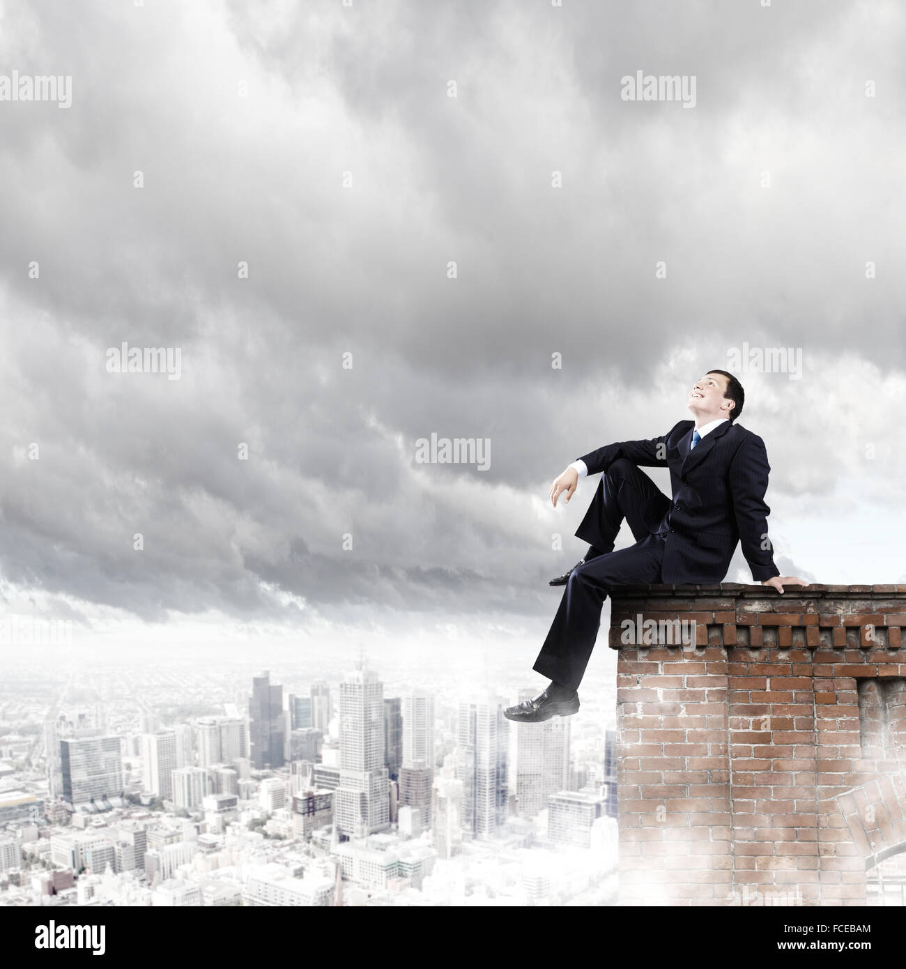 Young businessman sitting on roof of building Stock Photo - Alamy