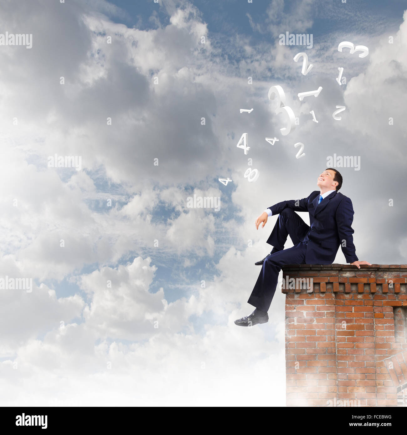 Young businessman sitting on roof of building Stock Photo - Alamy